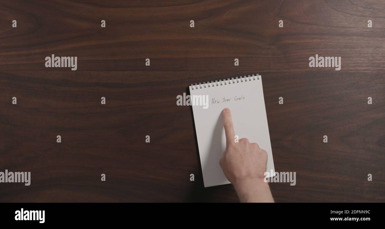 Top view man show notepad with new year goals on walnut wood table ...