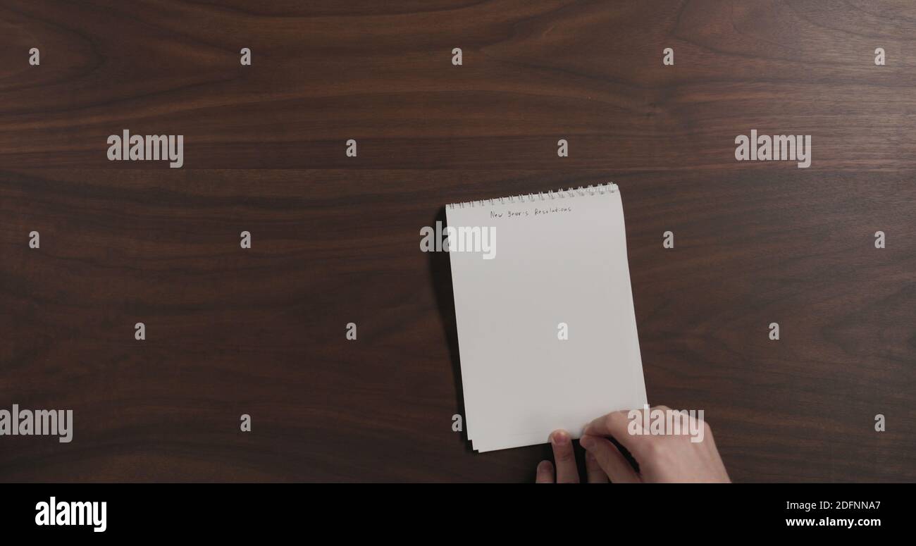 Top view man show notepad with new year goals on walnut wood table ...