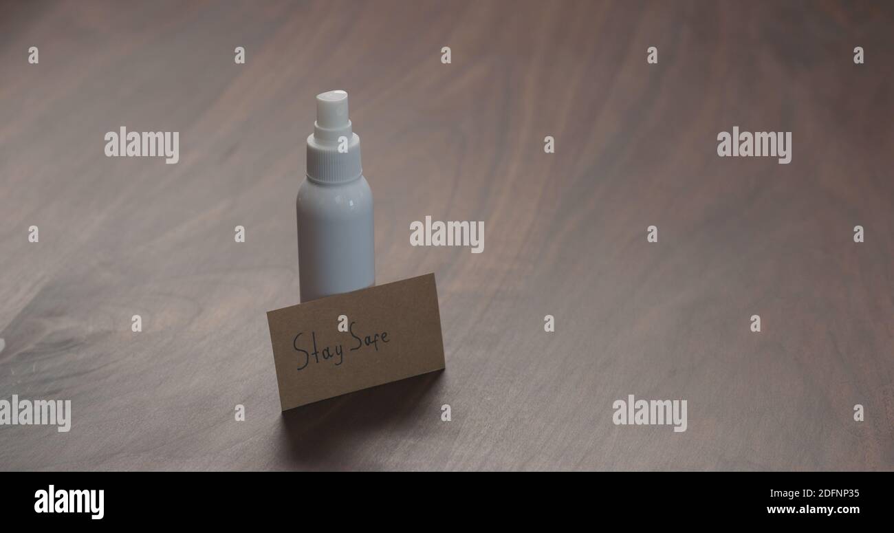 sanitizer white spray bottle on walnut wood table with stay safe card ...