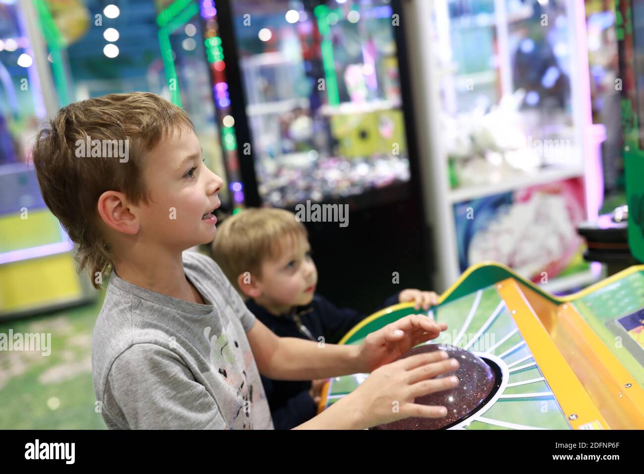 Brothers playing arcade game in amusement park Stock Photo - Alamy