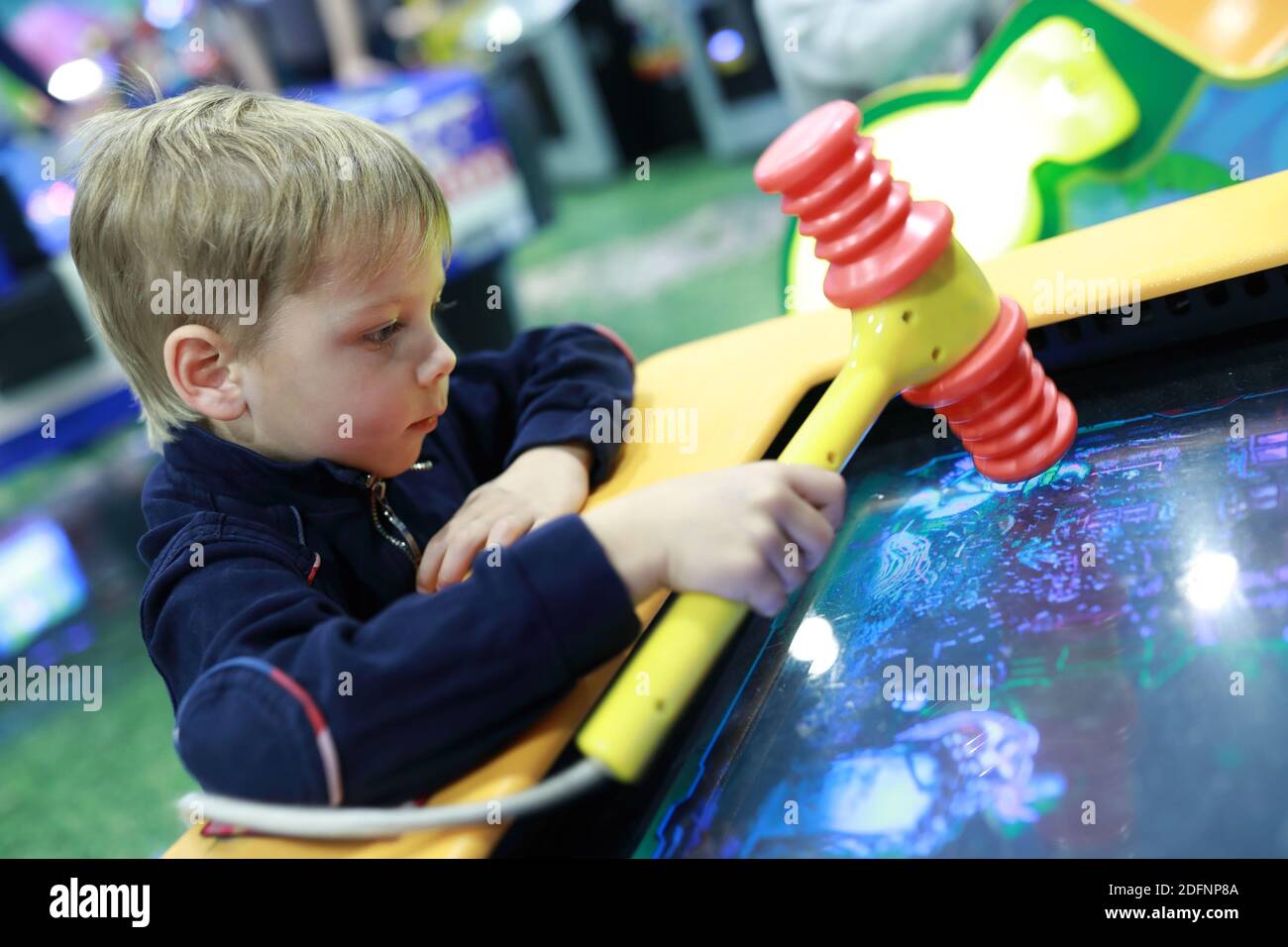 Child playing arcade game in amusement center Stock Photo - Alamy