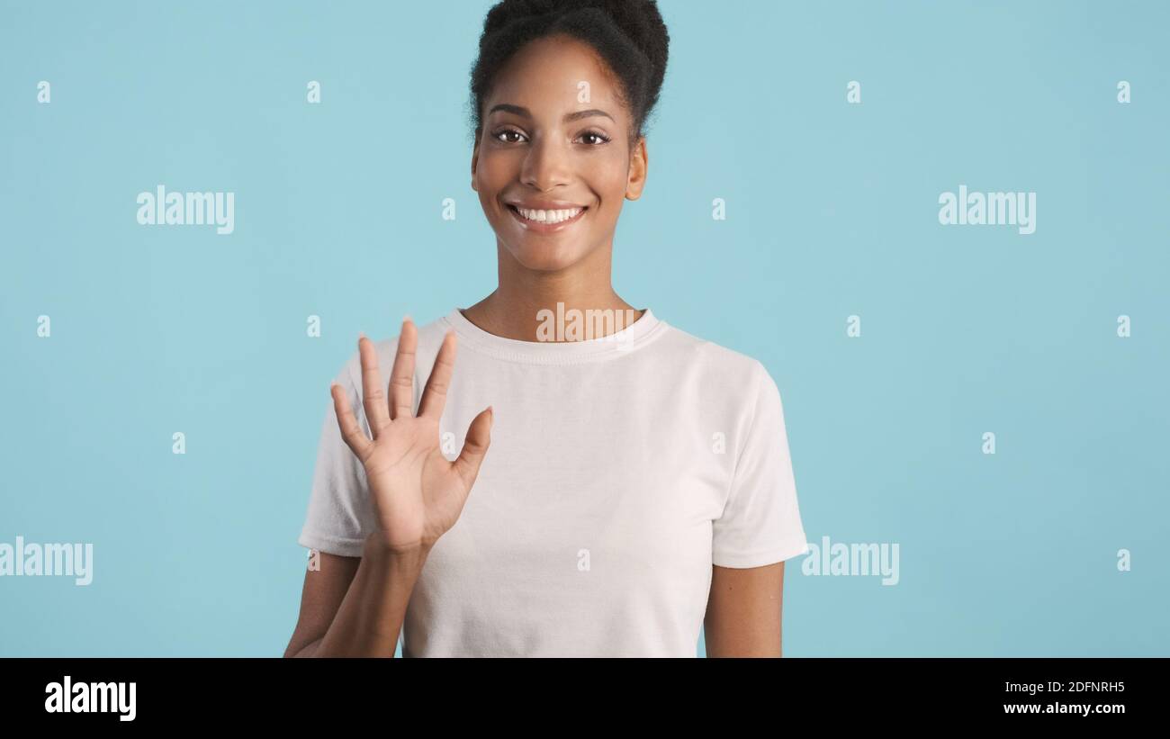 Beautiful African American girl happily waving hello on camera over ...