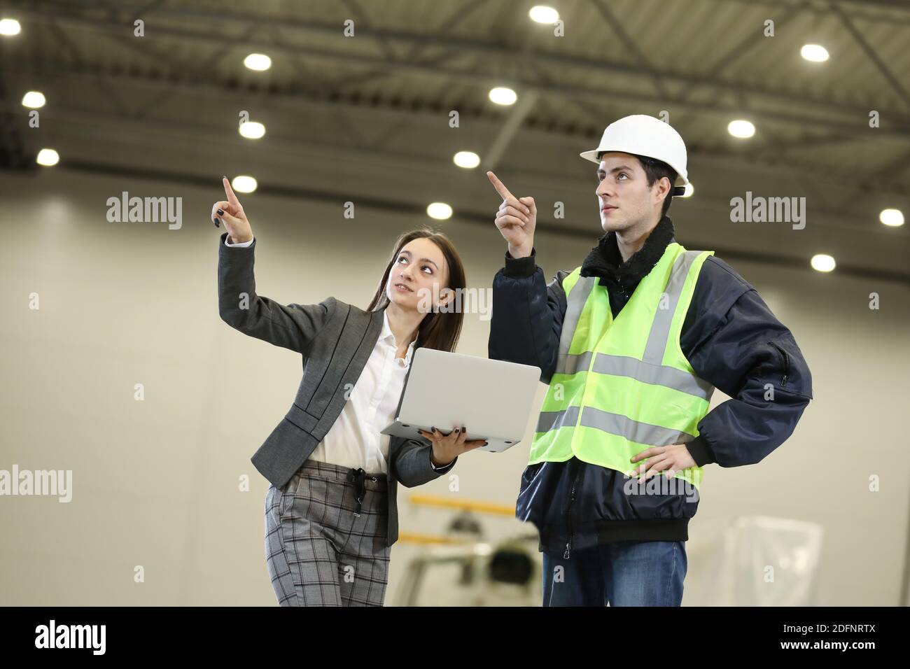 Portrait of a female factory manager in a white hard hat and business ...