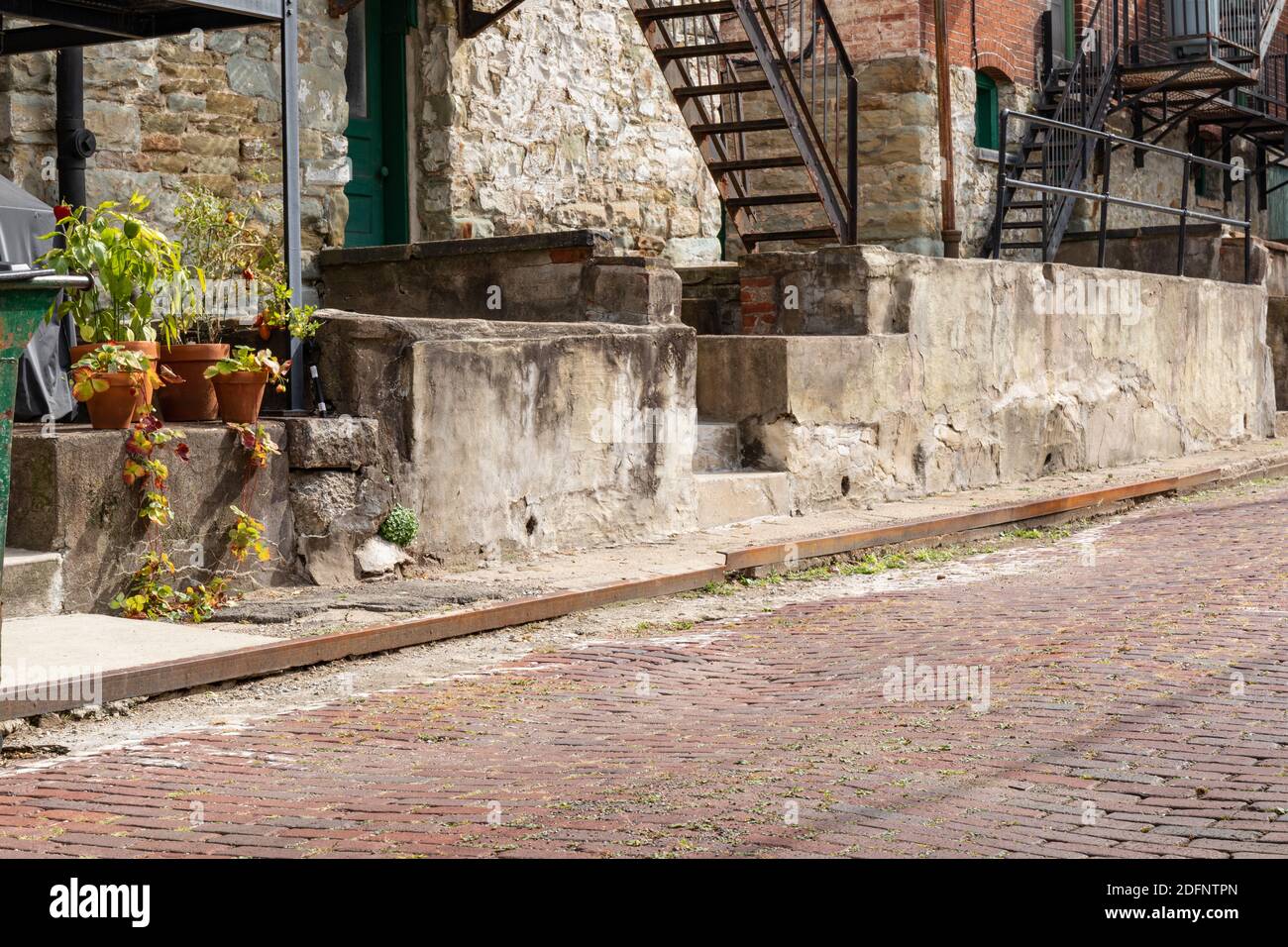 Red brick street with rusted metal curb edge, patched concrete ...