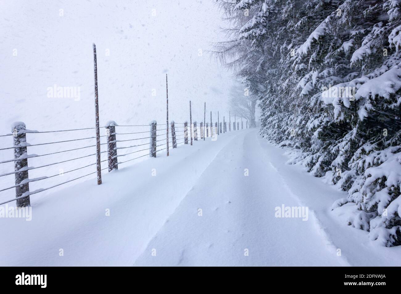 Frozen rural street in the Austrian alps covered in snow during a heavy ...