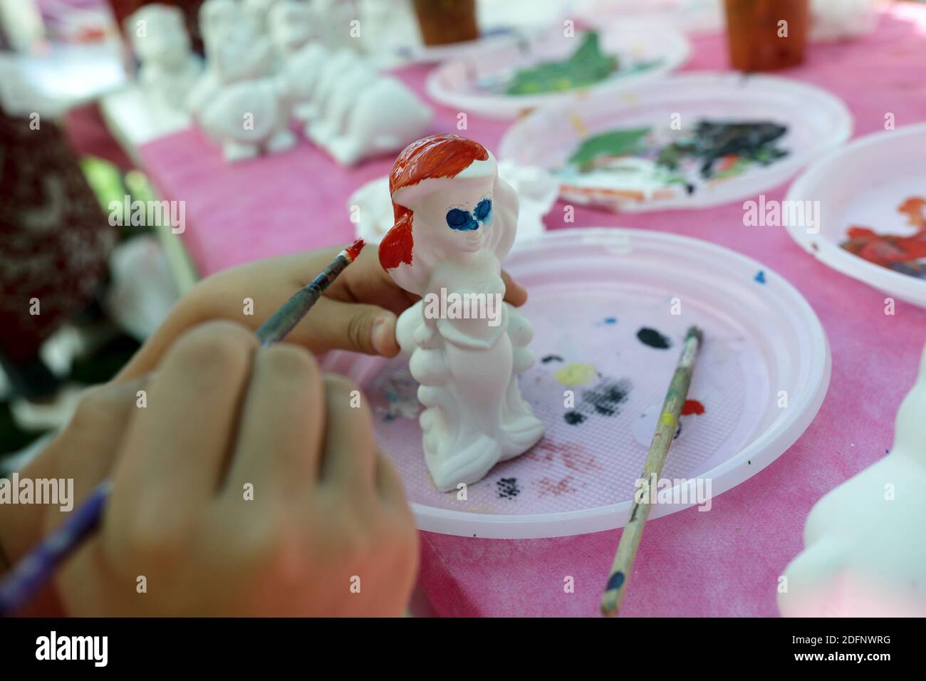 Person painting a plaster figure at table Stock Photo - Alamy