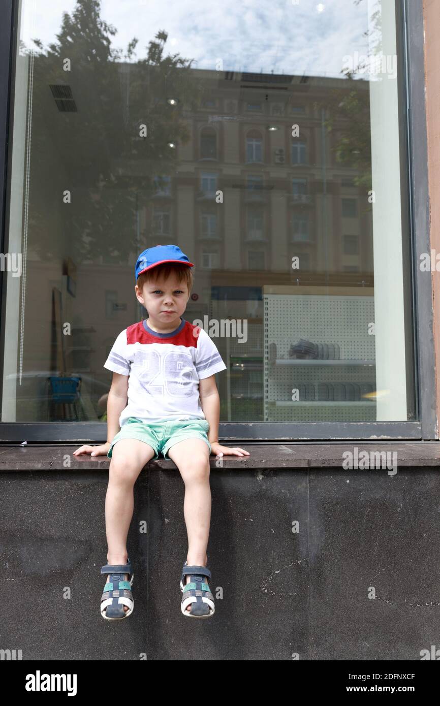 Kid sitting on windowsill from side of street Stock Photo - Alamy