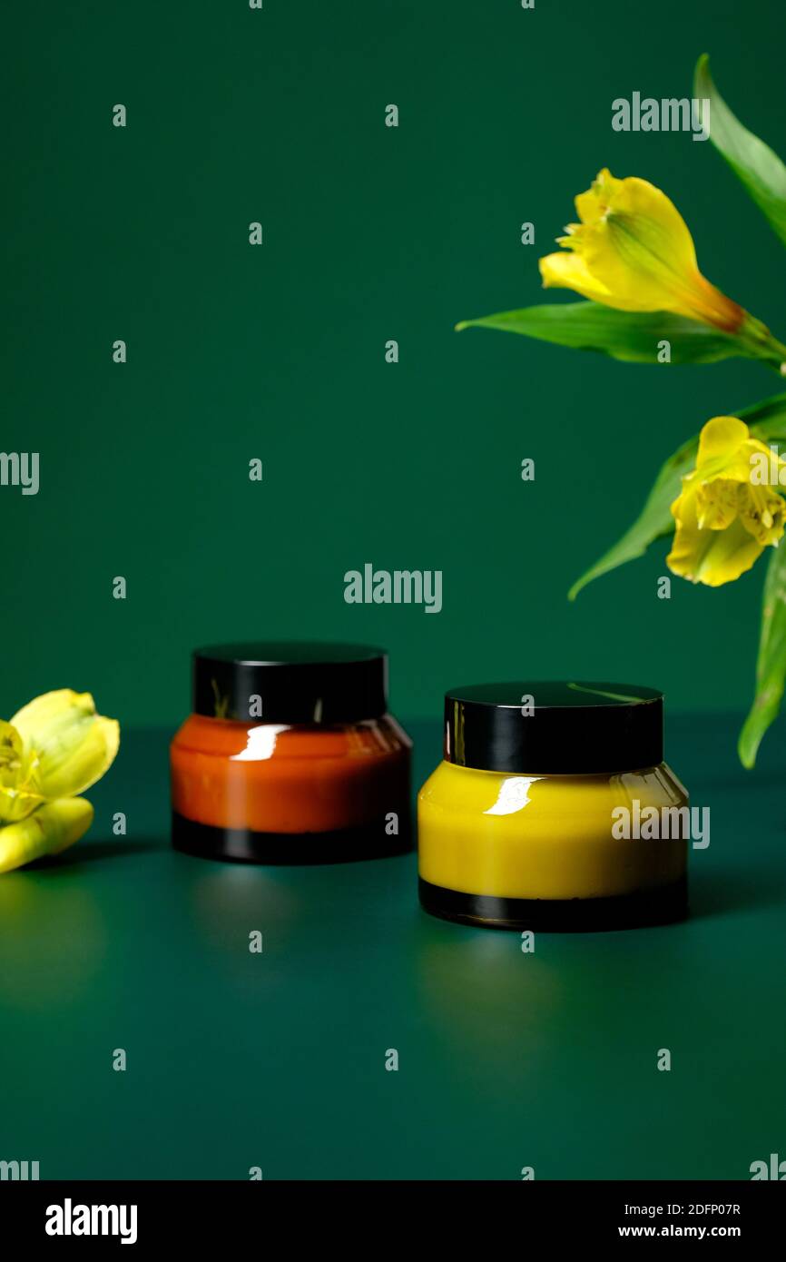 Herbal moisturizing cream jars and flowers on green background. Natural ...