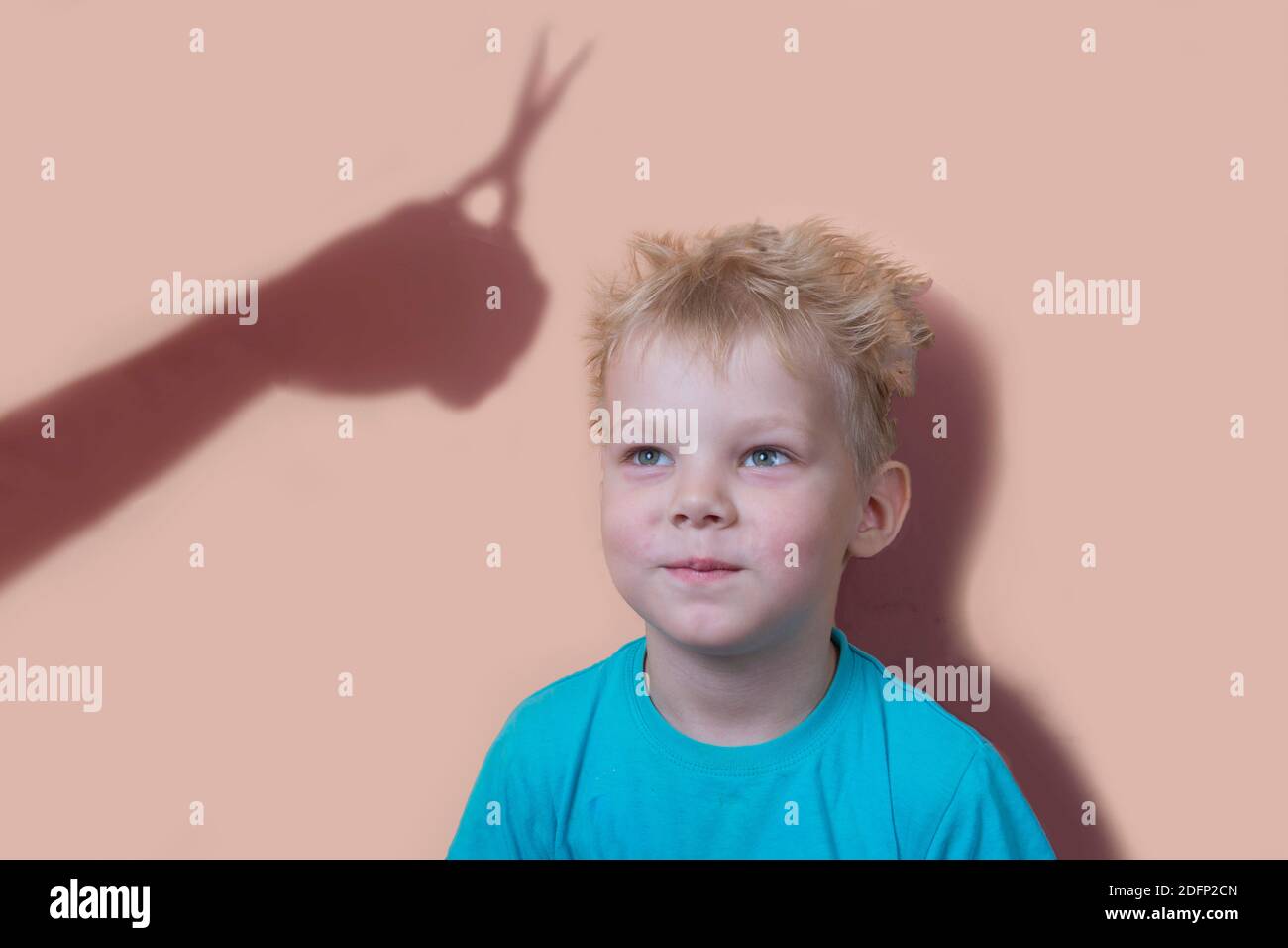 the shaggy boy looks at the hand off-screen.Hair cutting. the shadow of ...