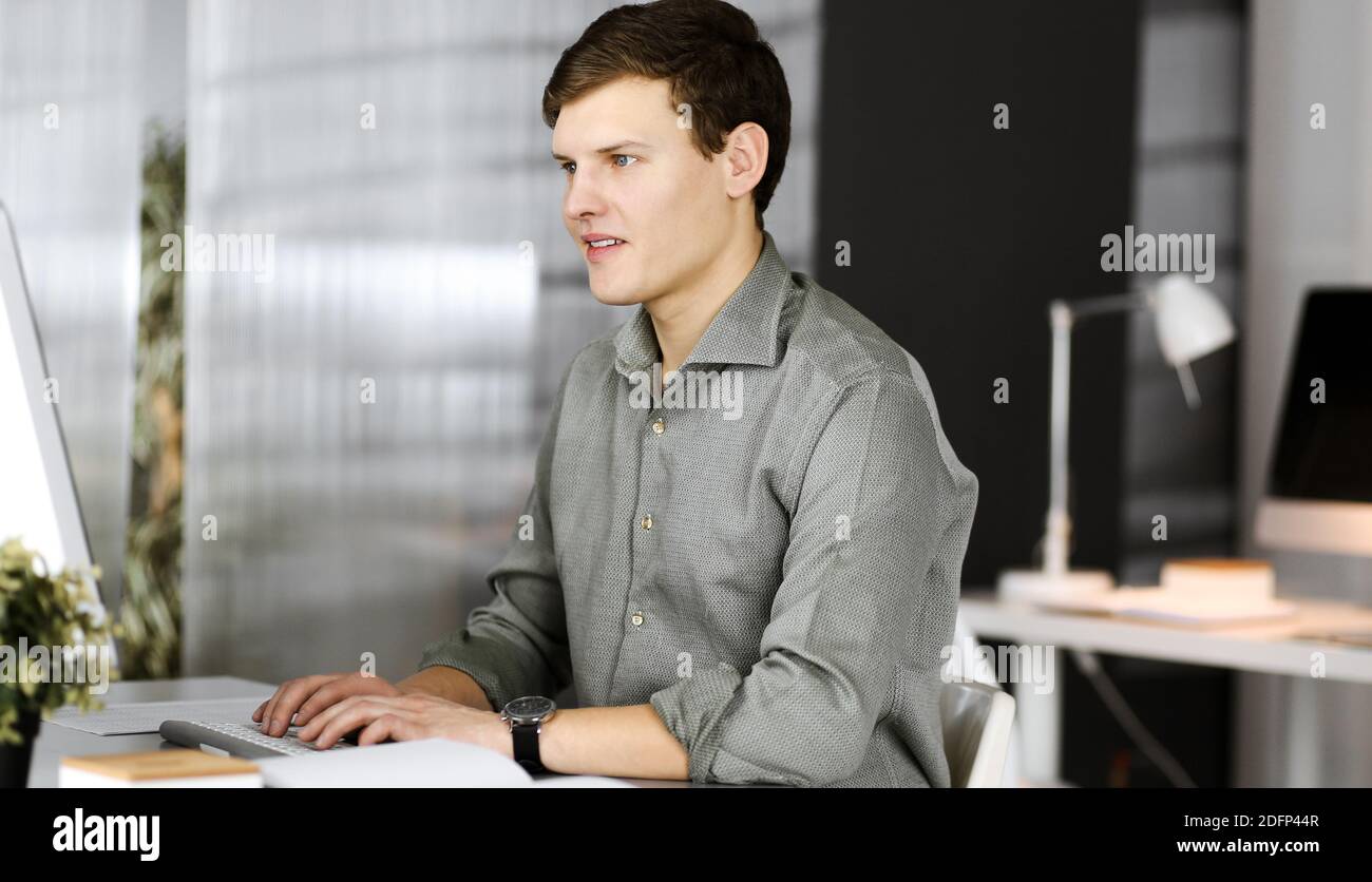 Sucessful young businessman and programmer in a green shirt is working ...