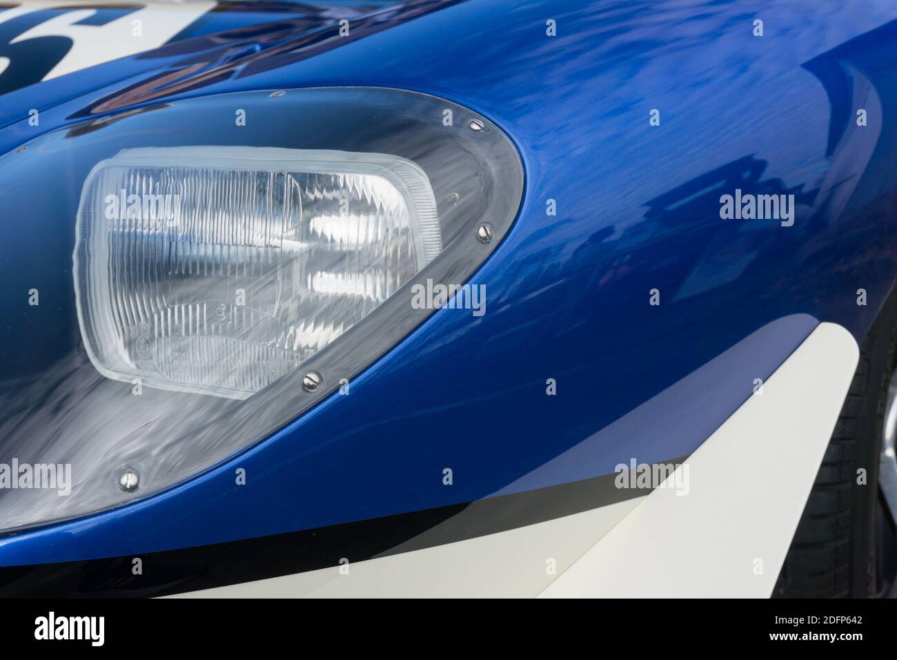 Close up detail of the headlight and bodywork of a metallic blue and ...
