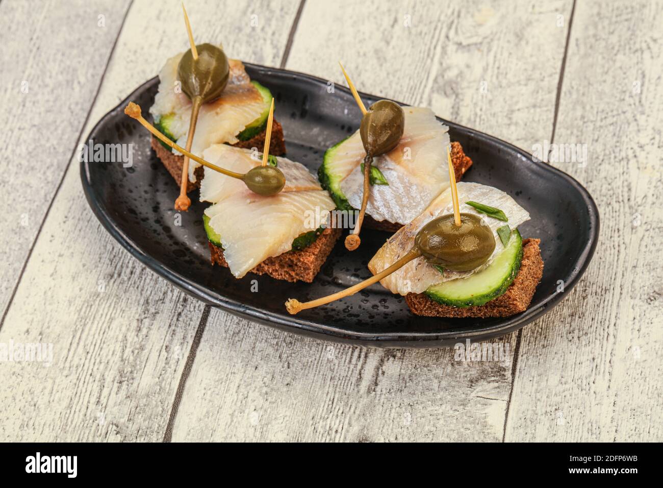 Herring fillet canape snack with caperberry and cucumber Stock Photo ...