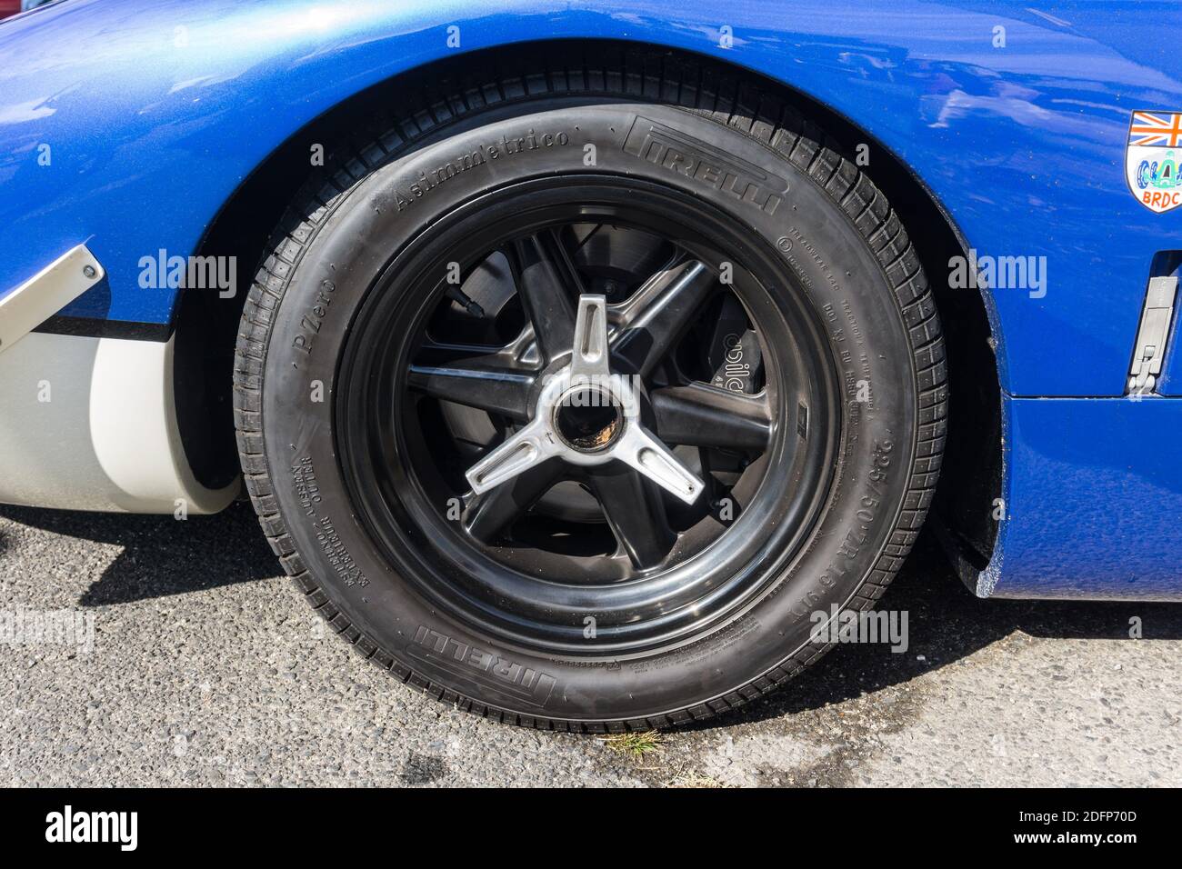 Close up detail of the black alloy wheel and spinner of a metallic blue ...
