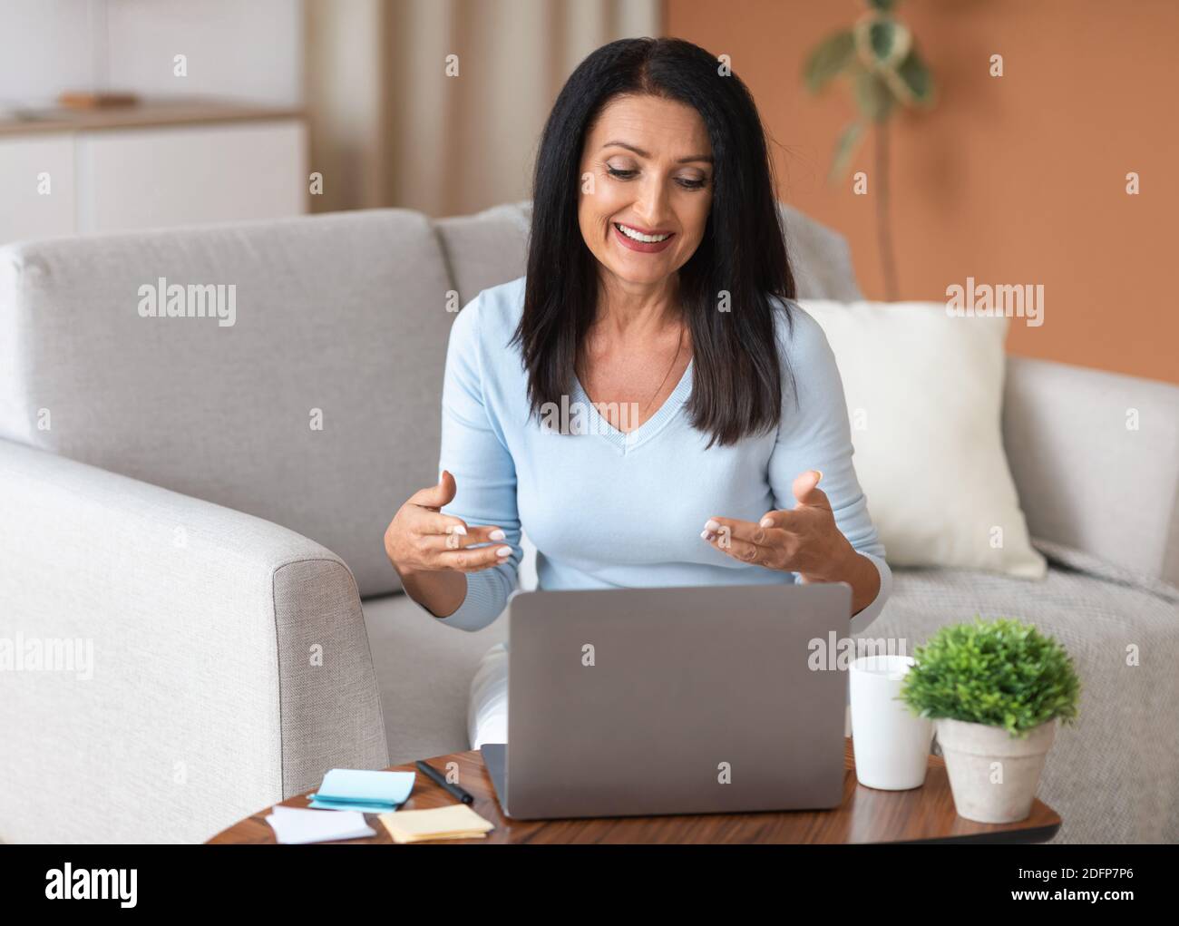 Woman sitting on couch, having video call on computer Stock Photo - Alamy