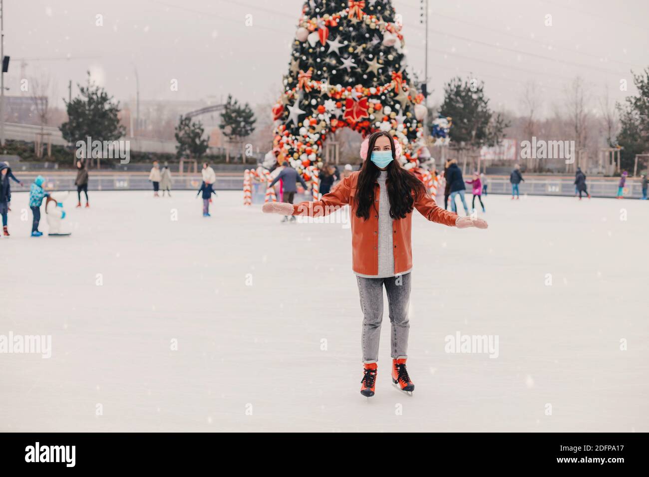 Beautiful young woman in pink earmuffs, medical face mask learn to ...