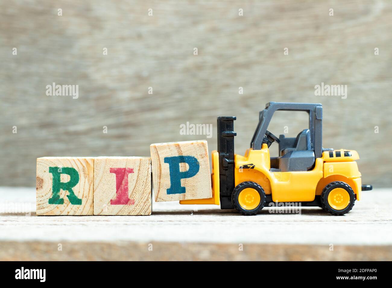 Toy forklift hold letter block P to complete word RIP (abbreviation of ...