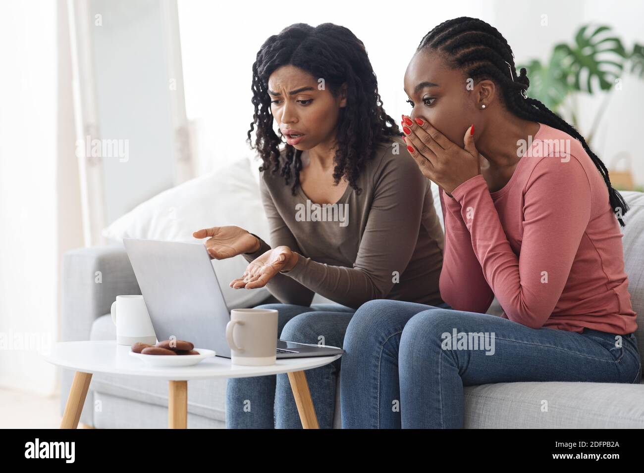 Confused black girlfriends sitting in front of laptop Stock Photo - Alamy