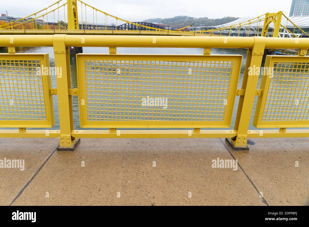 Yellow safety railing alongside the sidewalk of a suspension bridge ...