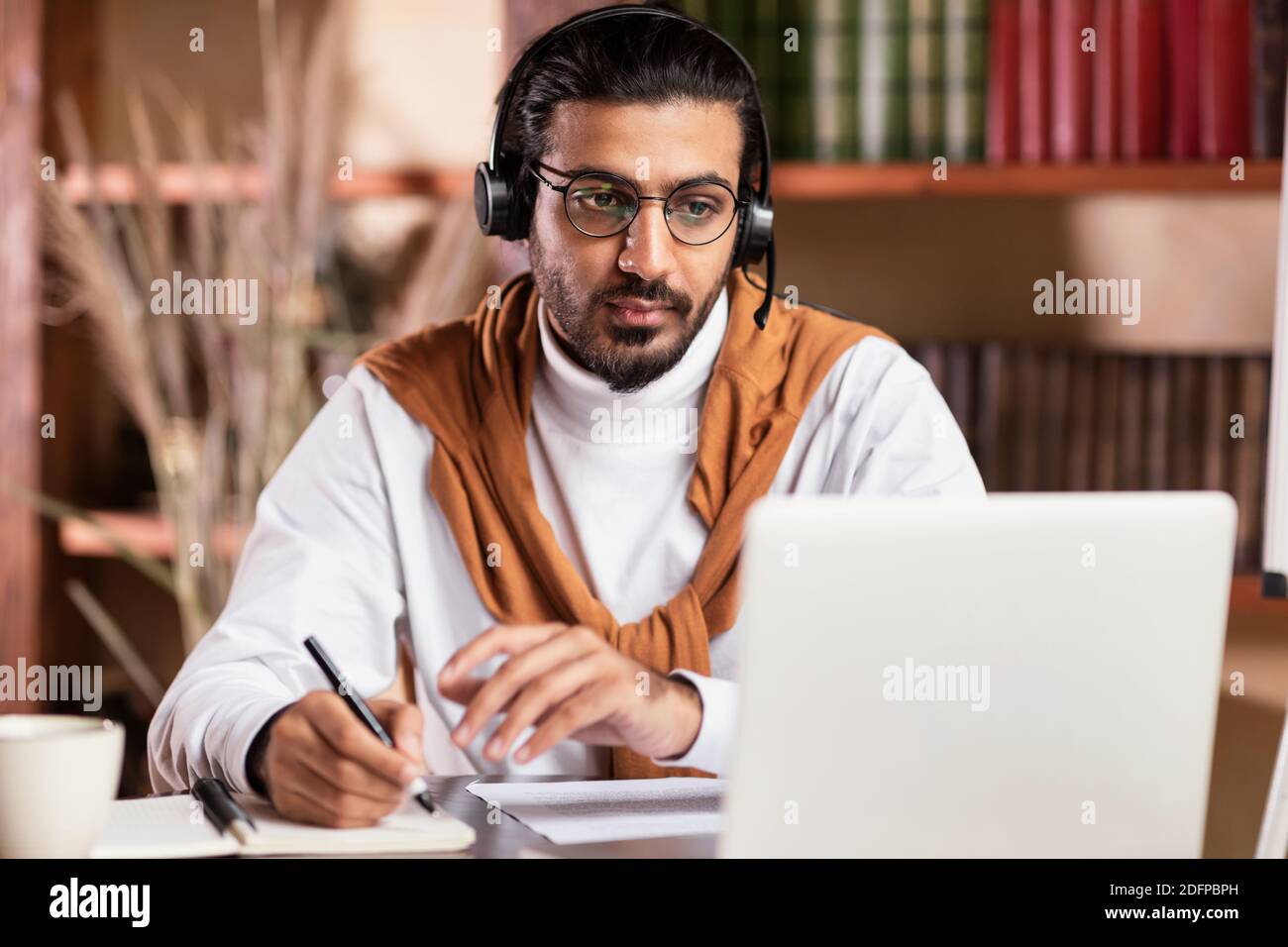 Indian Student Studying Online At Laptop Wearing Headset Sitting Indoor ...