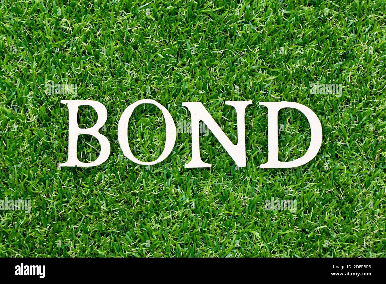Wood letter in word bond on green grass background Stock Photo - Alamy