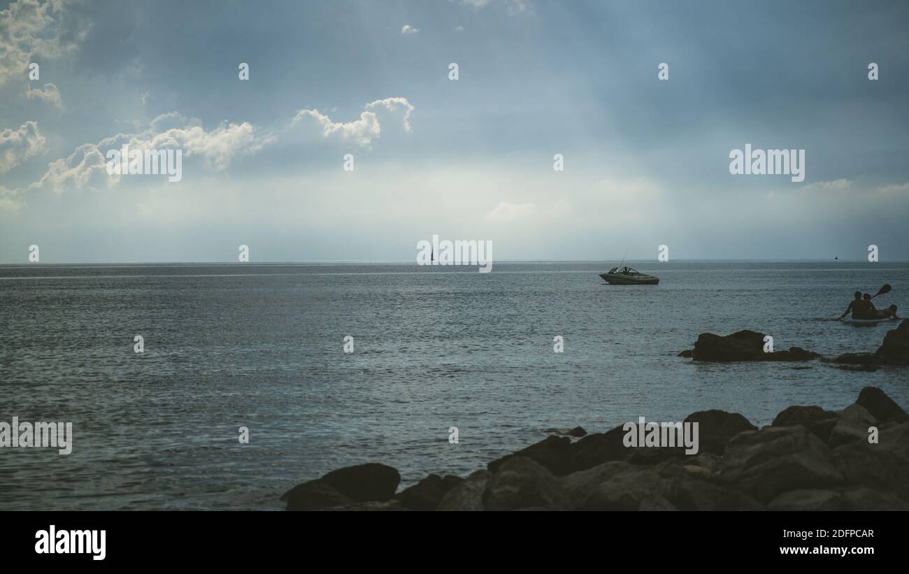 A majestic wavy sea under a dramatic heavy cloudscape with bright sun ...