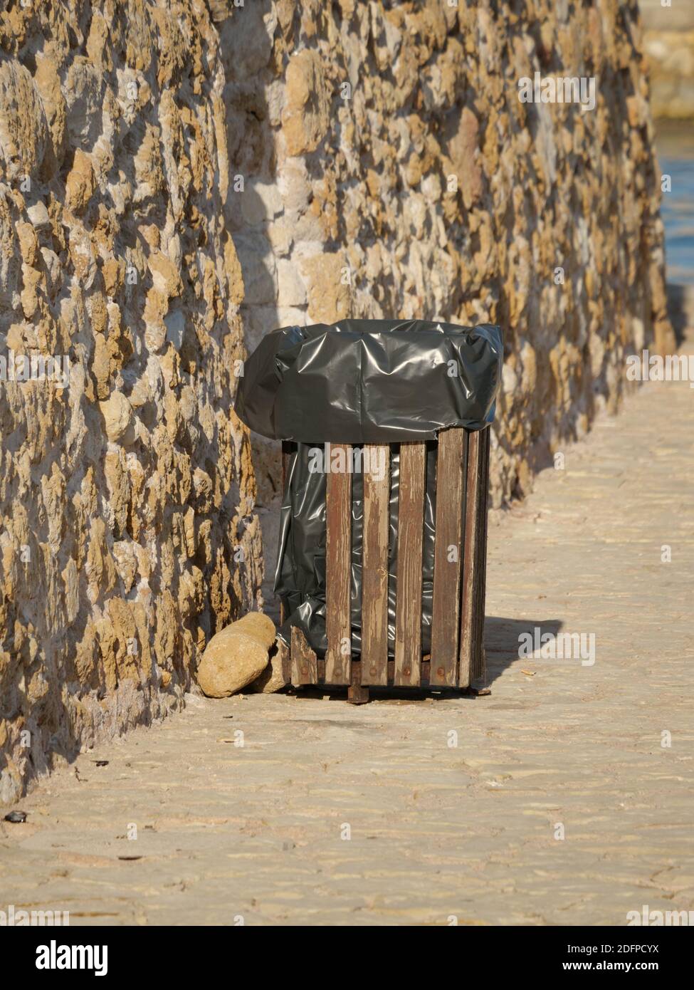 A vertical shot of a wooden trash bin with a black bag Stock Photo - Alamy