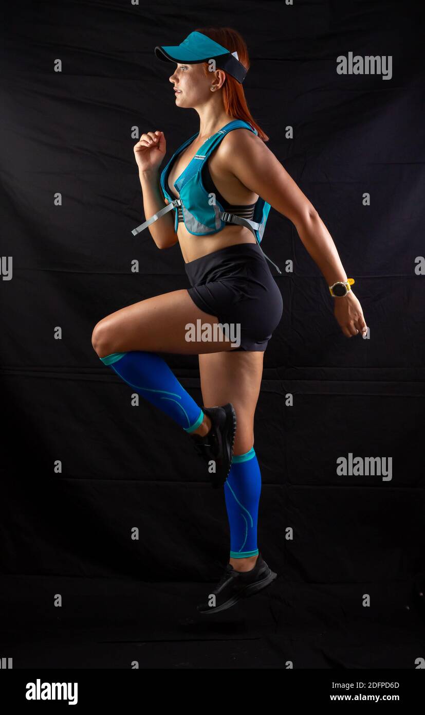 girl in blue jogging uniform runs in the studio on a black background ...