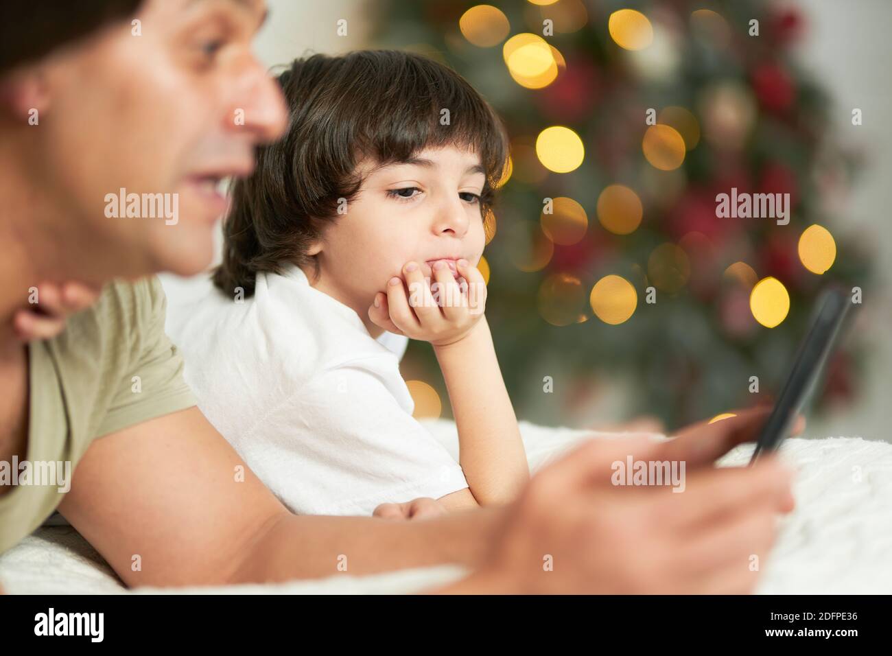 Cute little son watching his father using digital tablet, lying on the ...