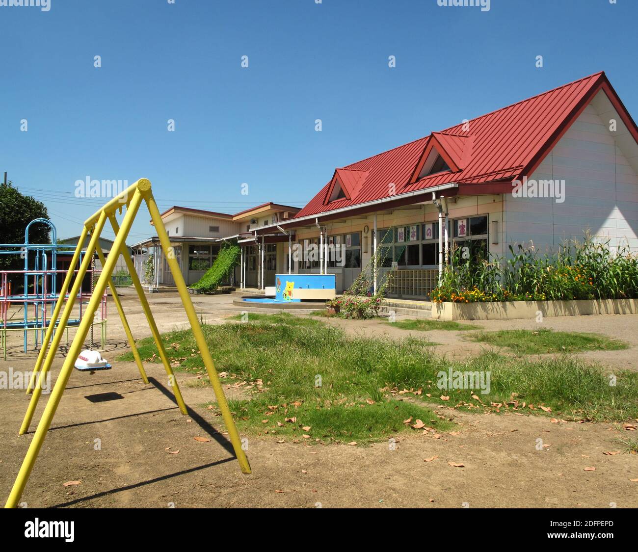 A traditional Japanese preschool with swings and bars in the playground ...