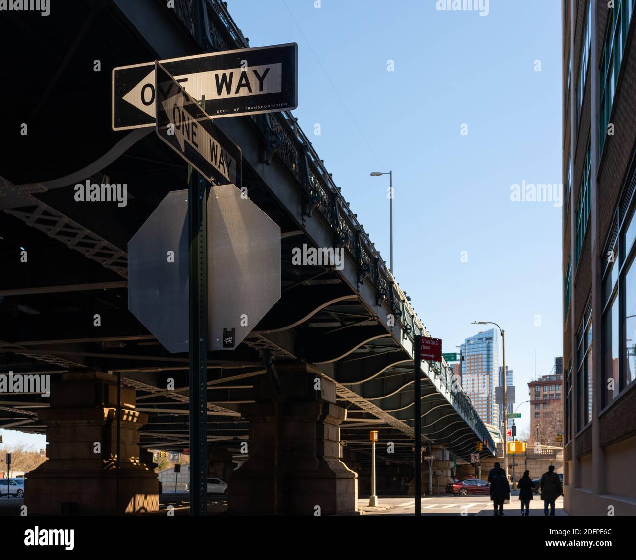 Two 'One Way' street signs intersecting under a bridge in dramatic ...
