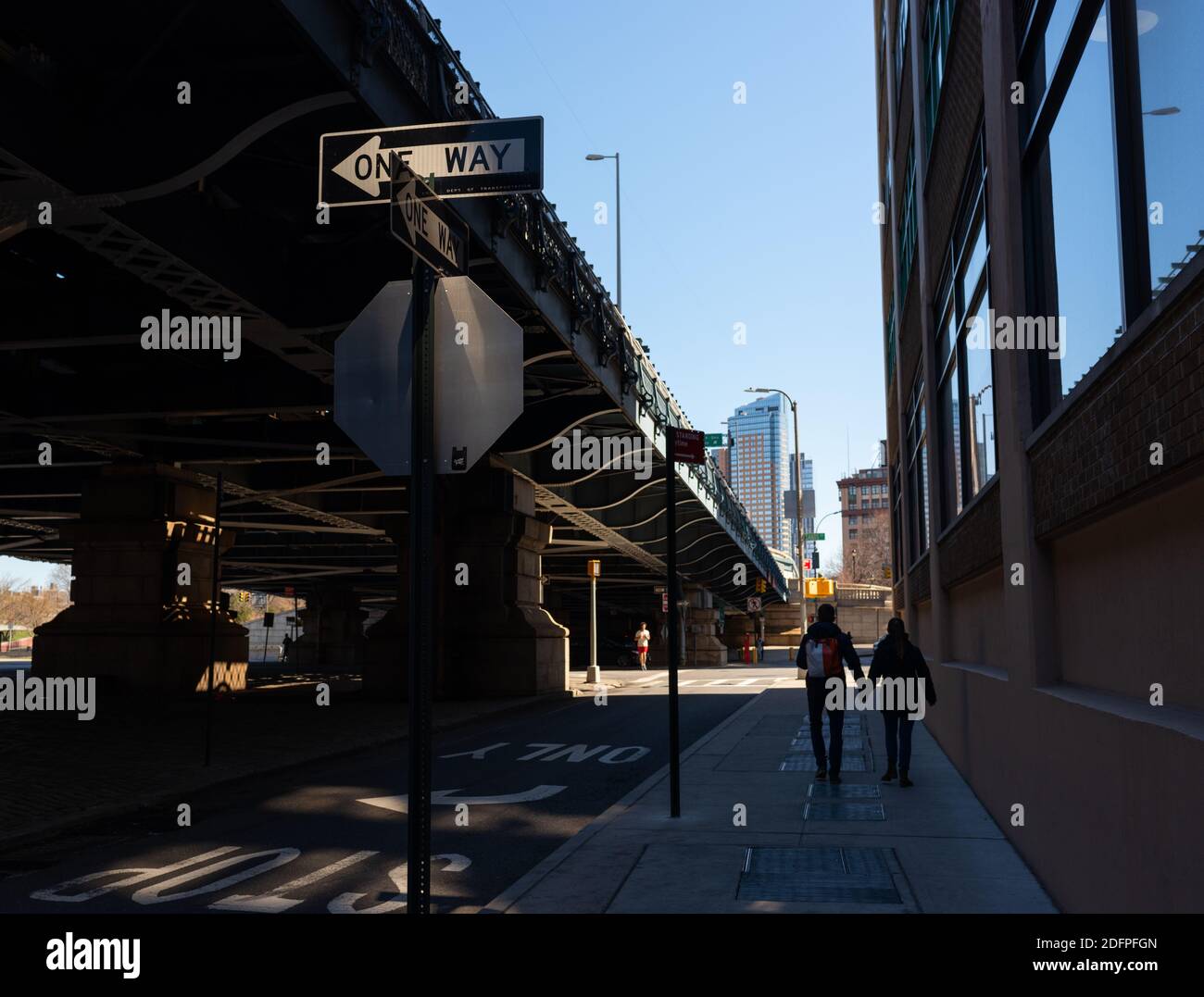 Two 'One Way' street signs intersecting under a bridge in dramatic ...