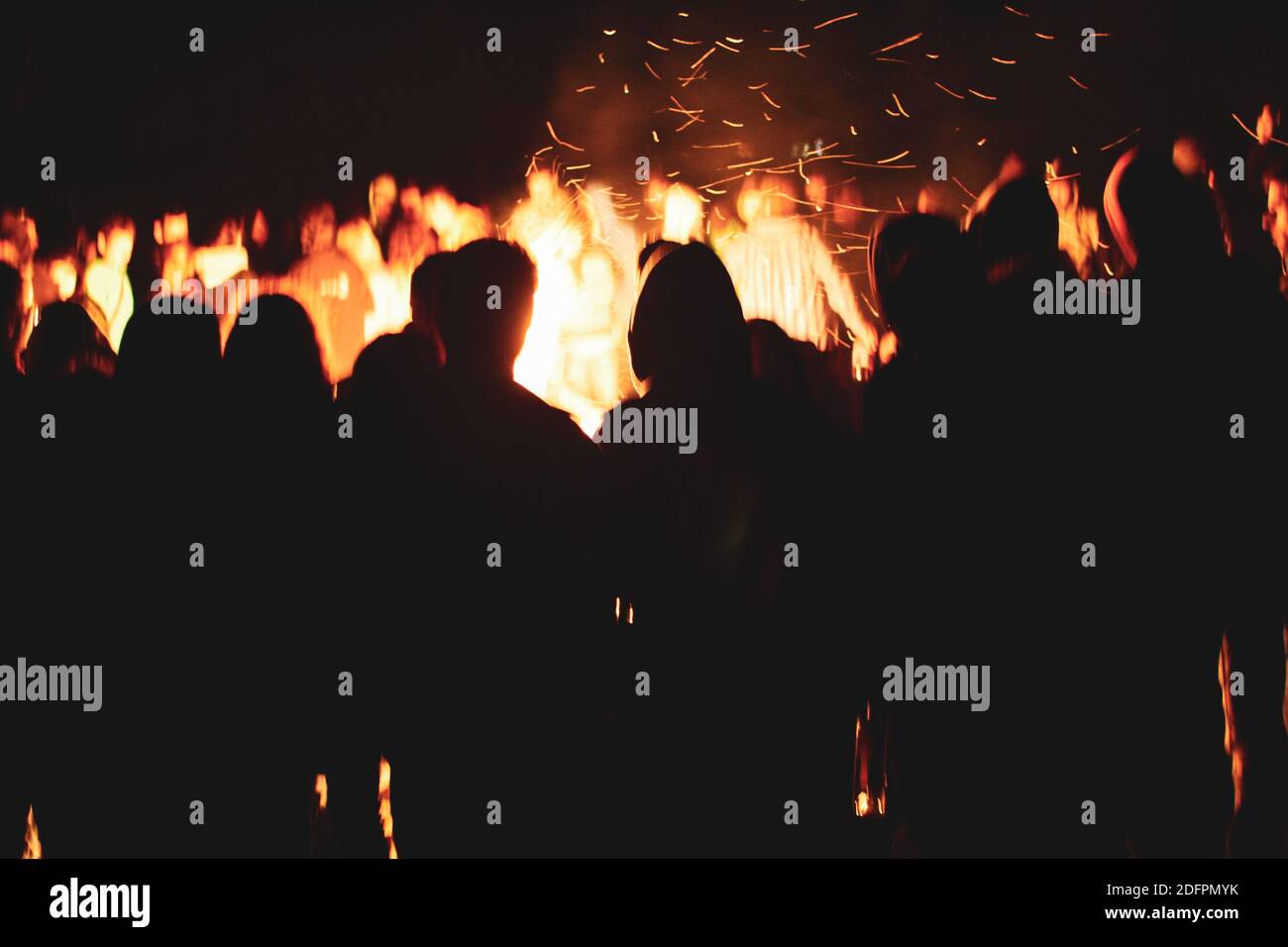 Moody and atmospheric image with people silhouetted against a fire on ...