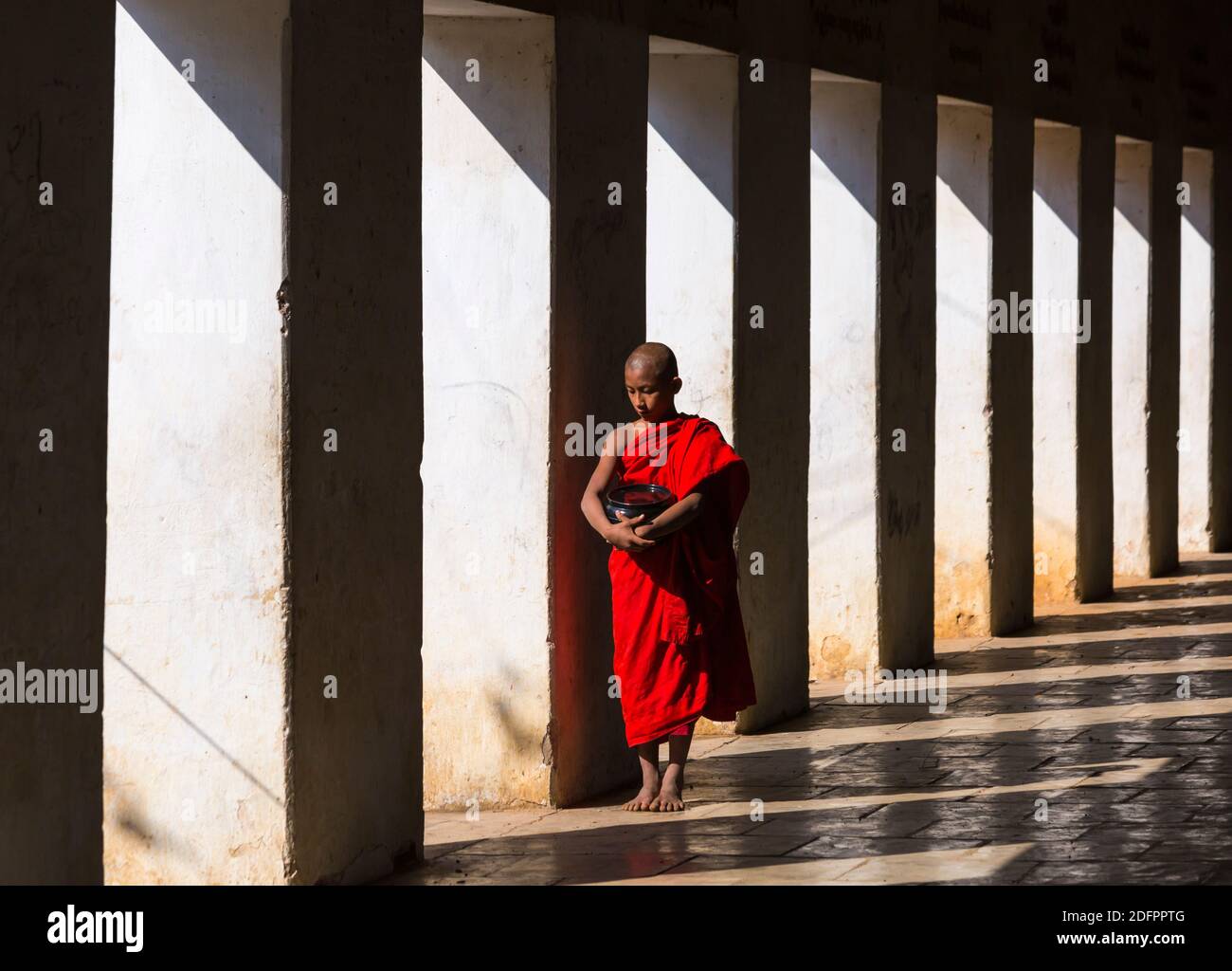 Novice Buddhist monk standing in eastern stair way of Shwezigon Pagoda ...