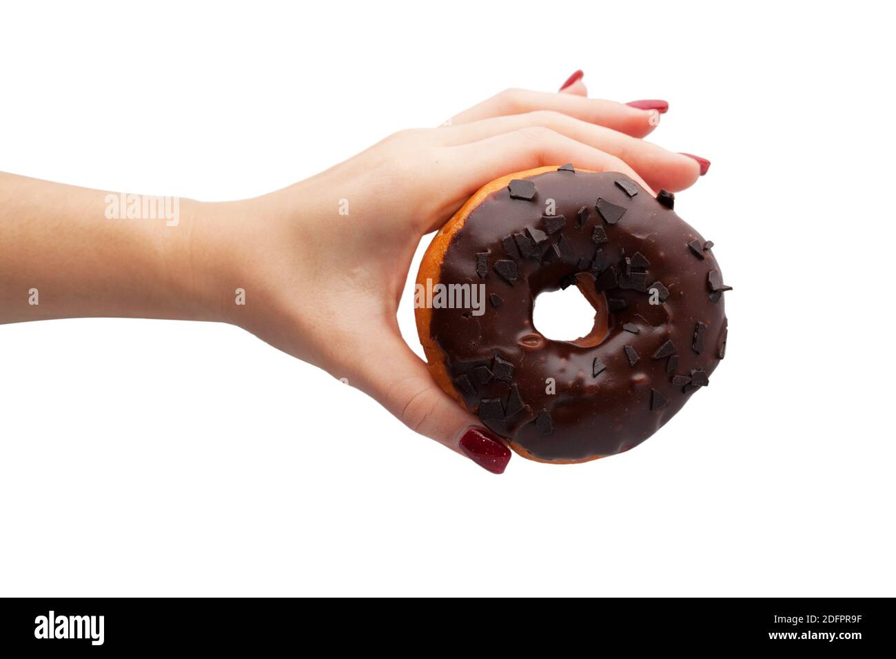 Female hand holds with fingers a chocolate brown donut in glaze ...