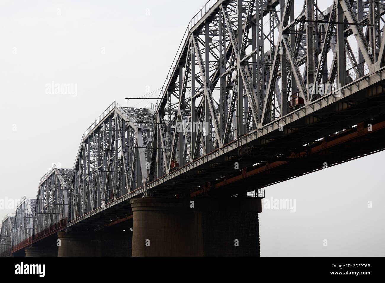bottom up view of several spans of a railway truss bridge against a ...