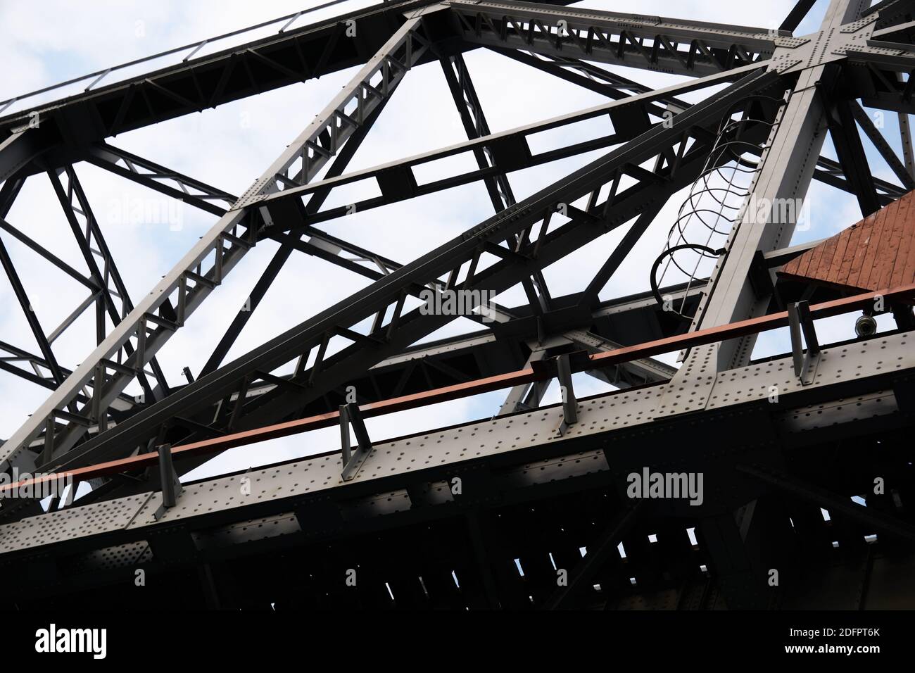 bottom up view of section of railway truss bridge against cloudy sky ...