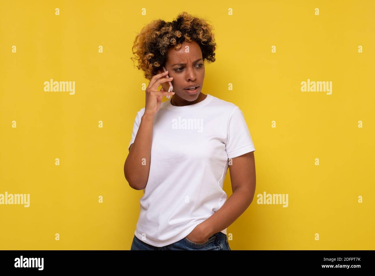 Young african woman talking on phone with her friend. Studio shot on ...