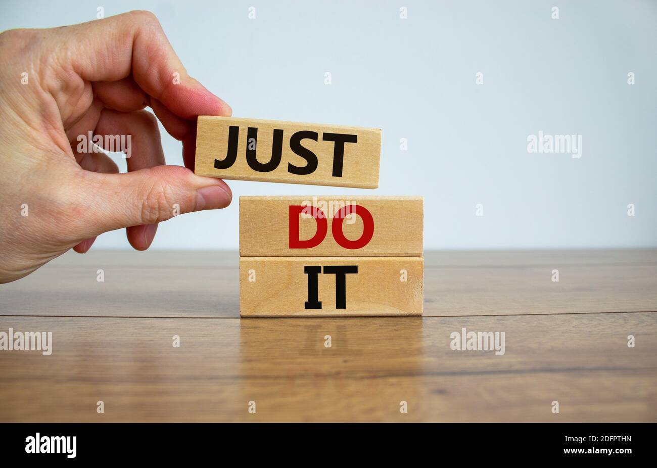 Just do it symbol. Male hand placing a block on top of a blocks tower ...