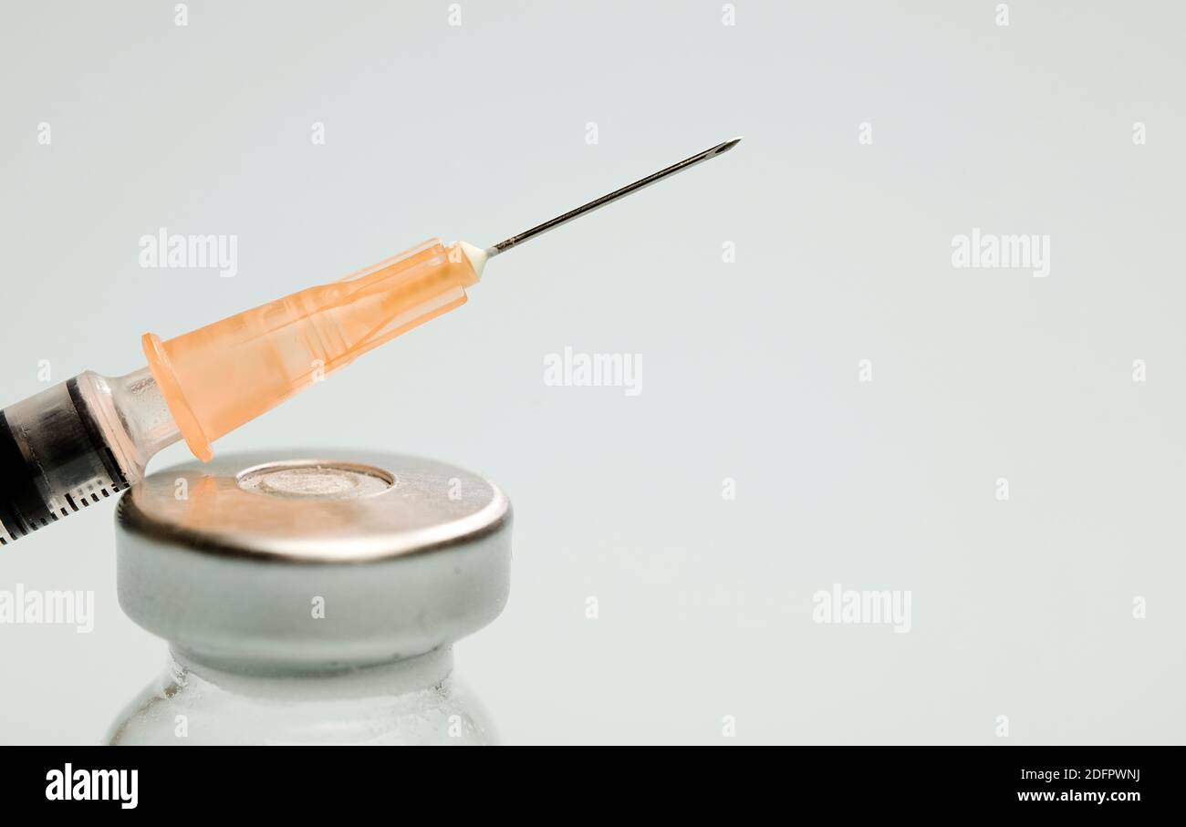 Vaccine vial with vaccination syringe, orange cannula and white ...