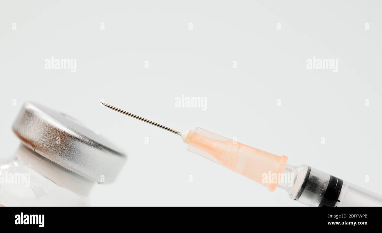 Vaccine vial with vaccination syringe, orange cannula and white ...