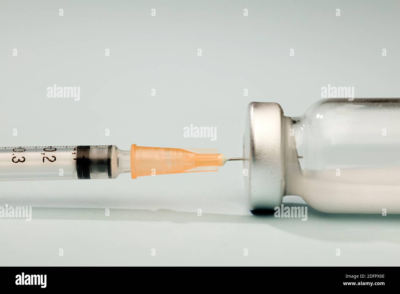 Vaccine vial with vaccination syringe, orange cannula and white ...