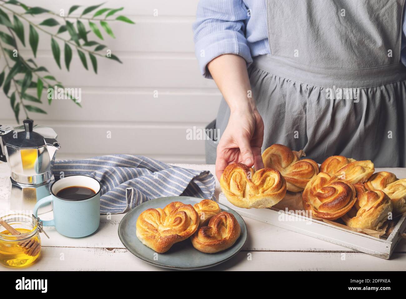 Homemade sweet buns in woman's hand. Serving breakfast at white rustic ...
