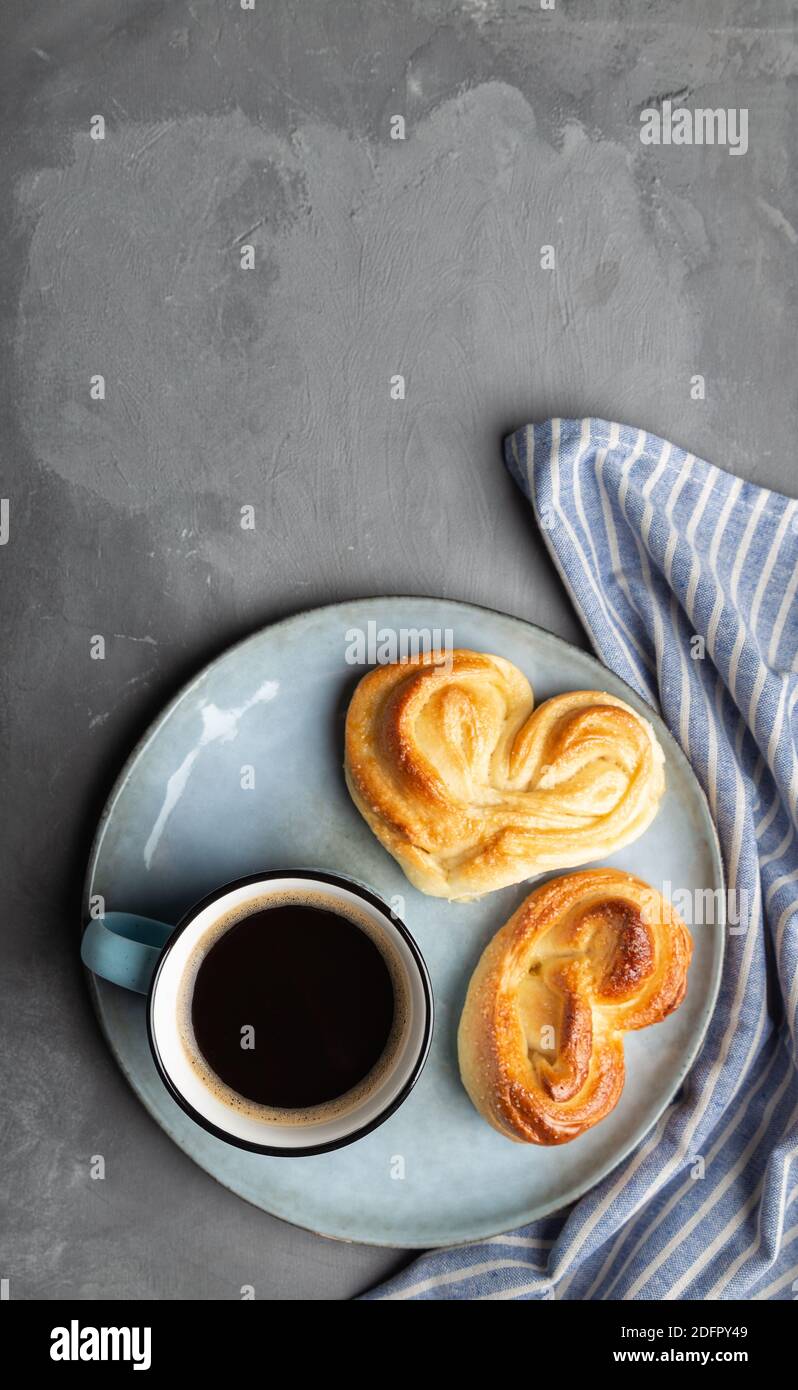 Cup of espresso coffee with two heart-shaped sweet buns in plate on ...
