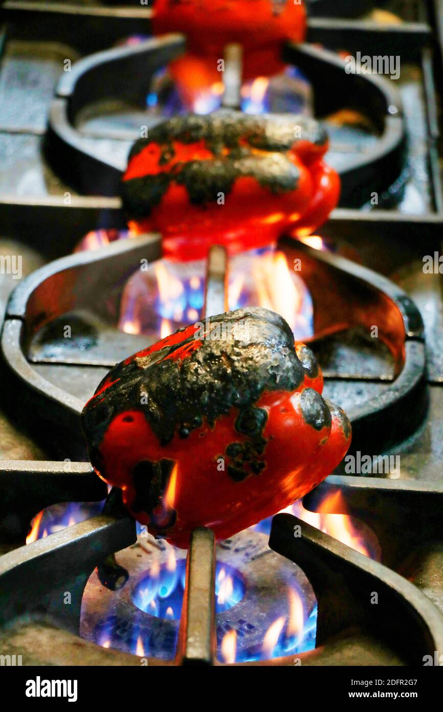 preparation of Roasted red peppers on direct flames in a kitchen Stock ...