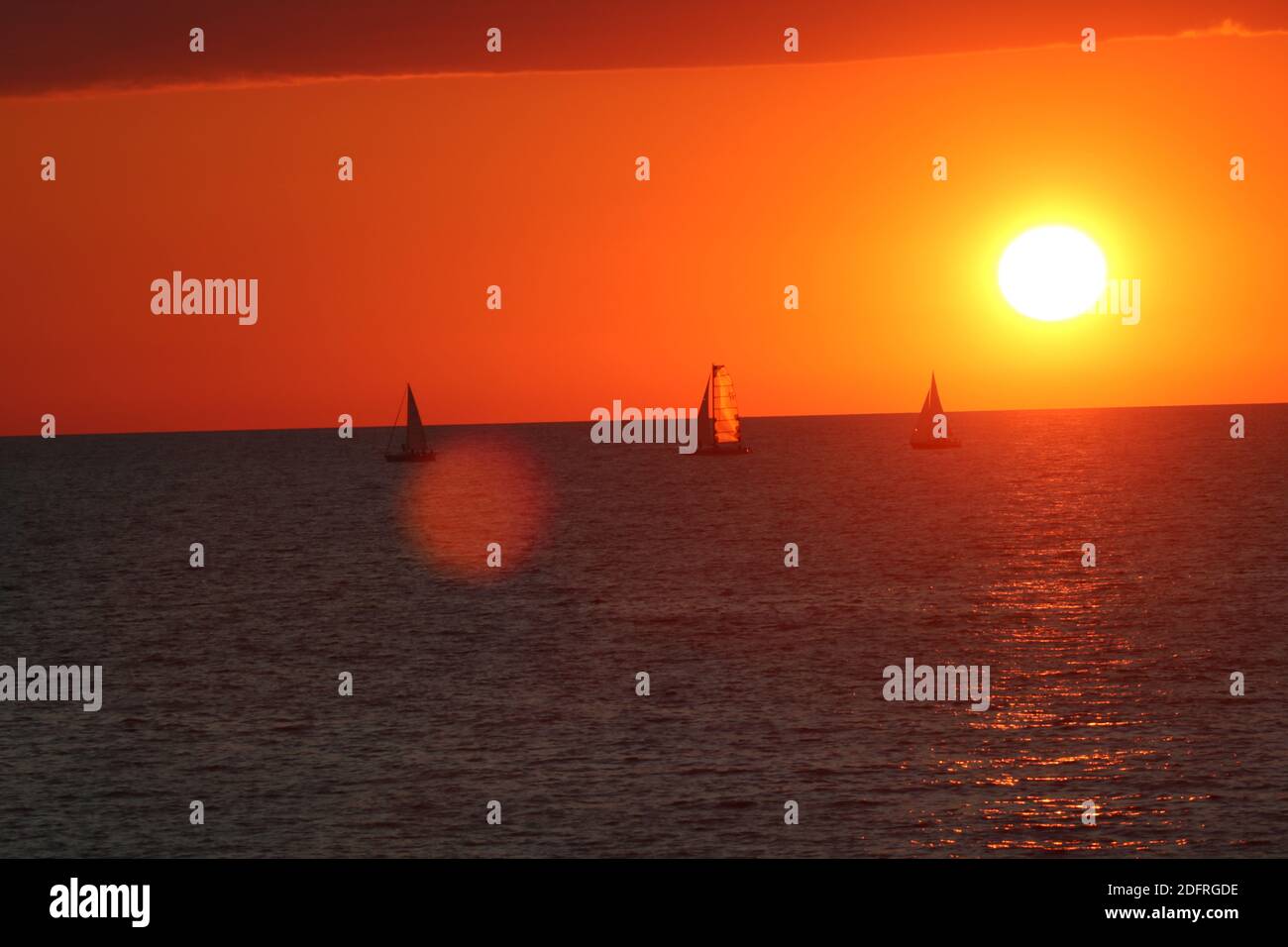 Sunset sailboats with lens flare Stock Photo - Alamy