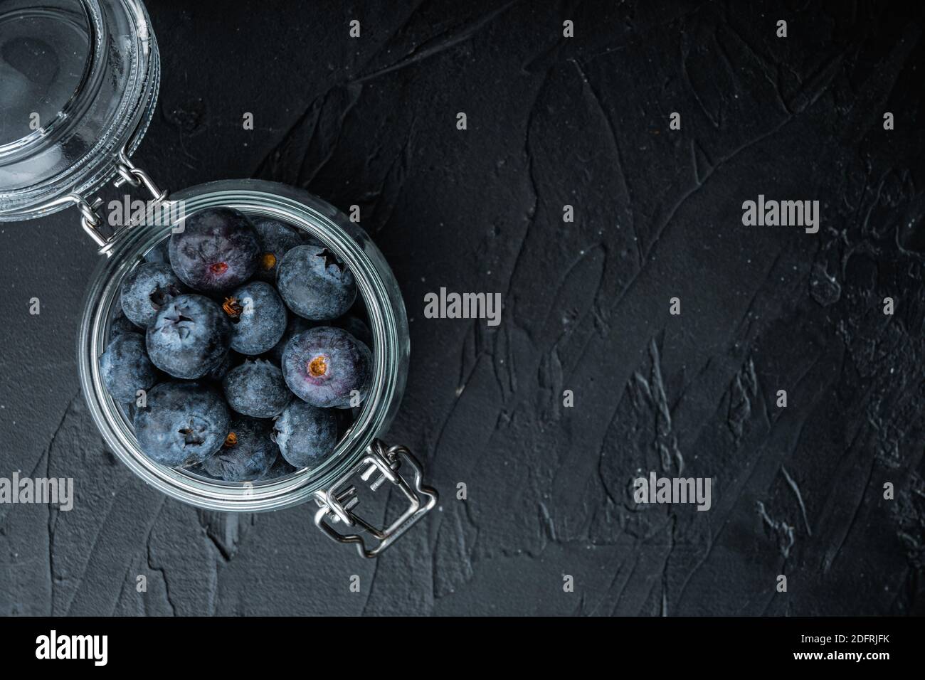 Ripe blueberry in glass jar, flat lay with space for text, on black ...