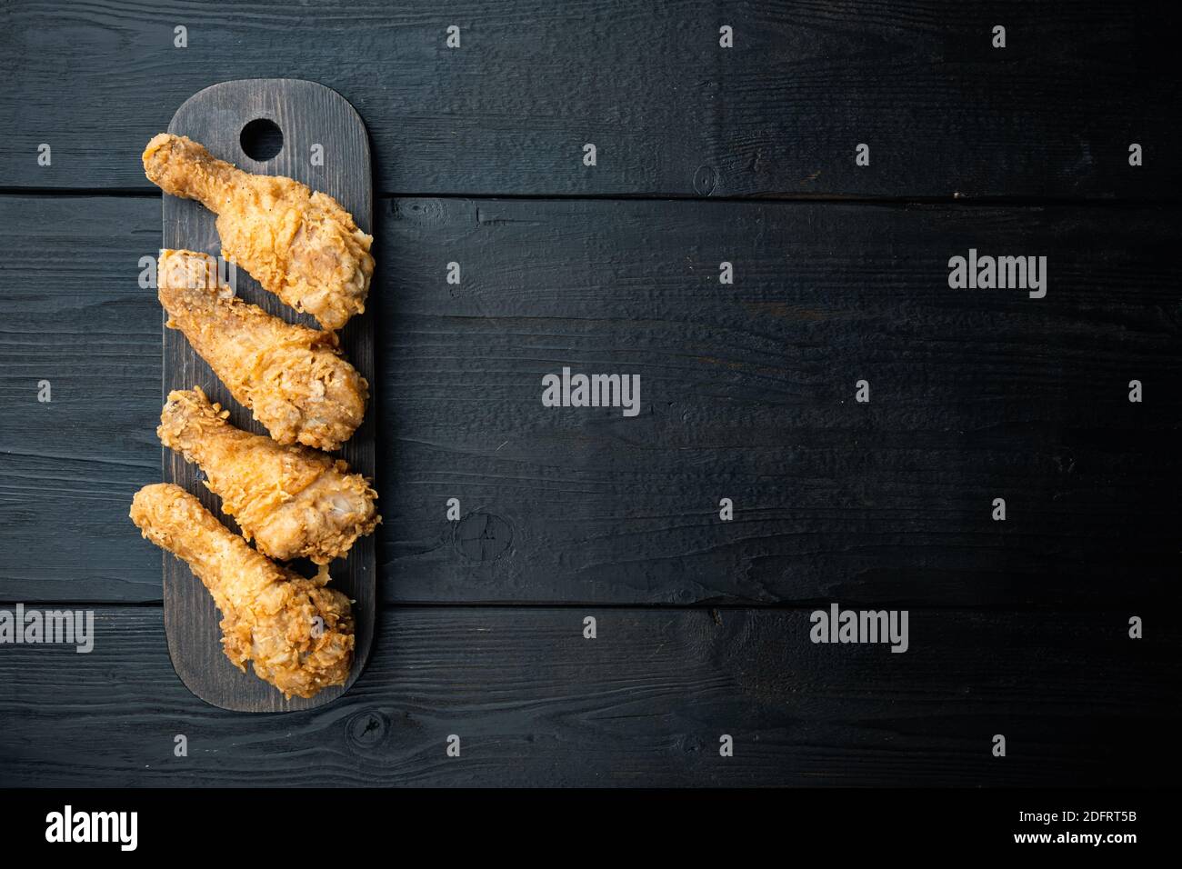 Chicken leg breaded and fried on black wooden background, flat lay ...