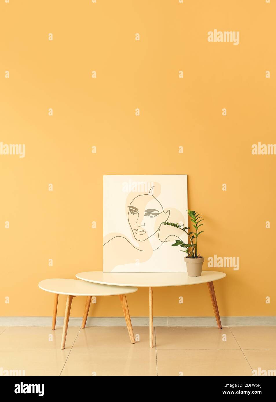Tables with beautiful picture near color wall in room Stock Photo - Alamy
