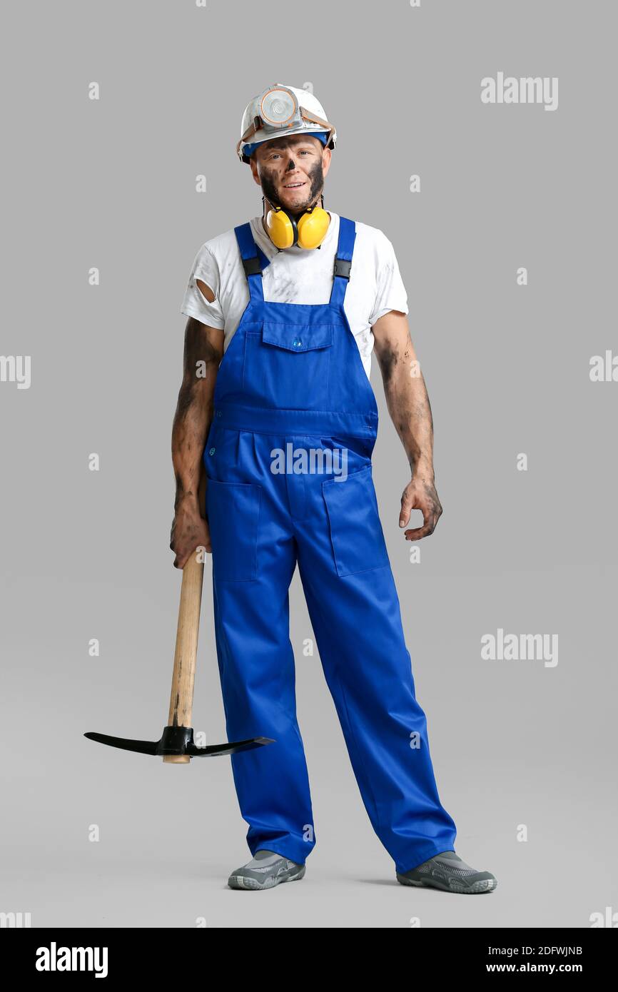 Miner man with pick axe on grey background Stock Photo - Alamy