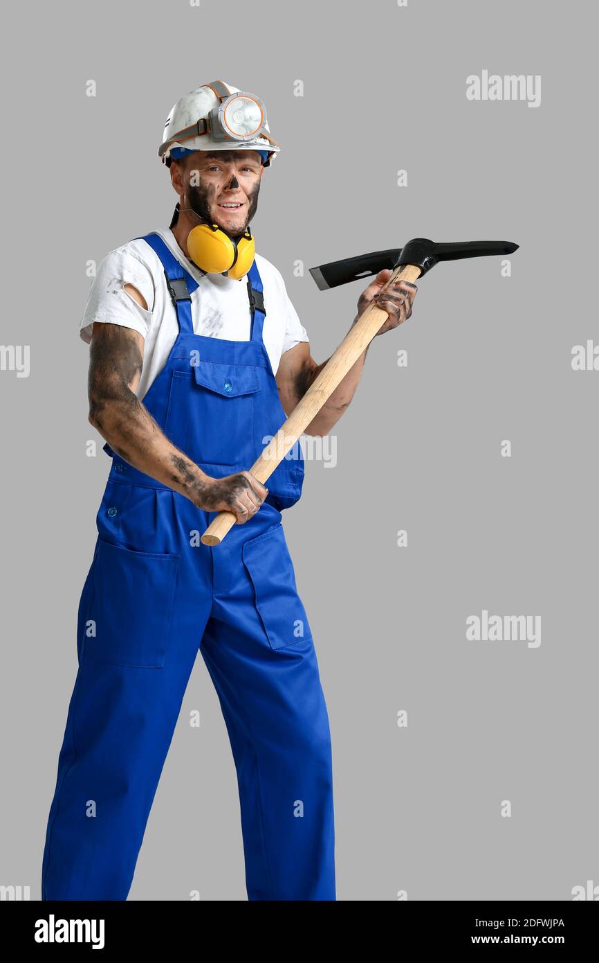 Miner man with pick axe on grey background Stock Photo - Alamy